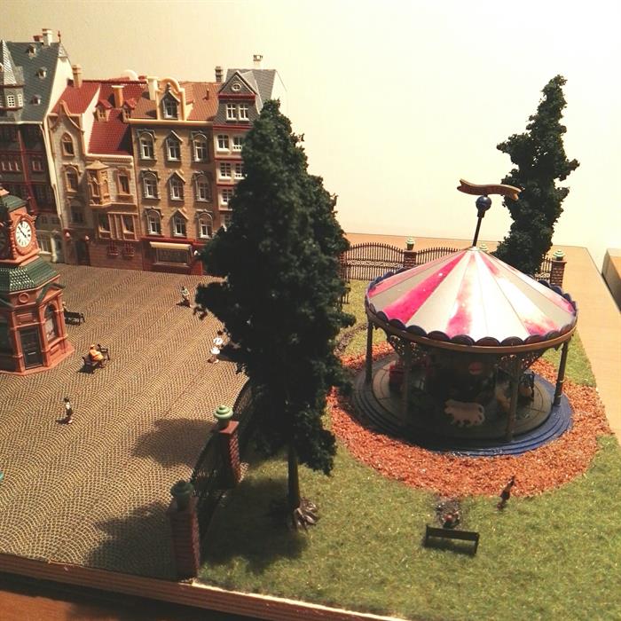 DIORAMA H0 PIAZZA CON OROGOLOGIO E GIARDINO CON GIOSTRA